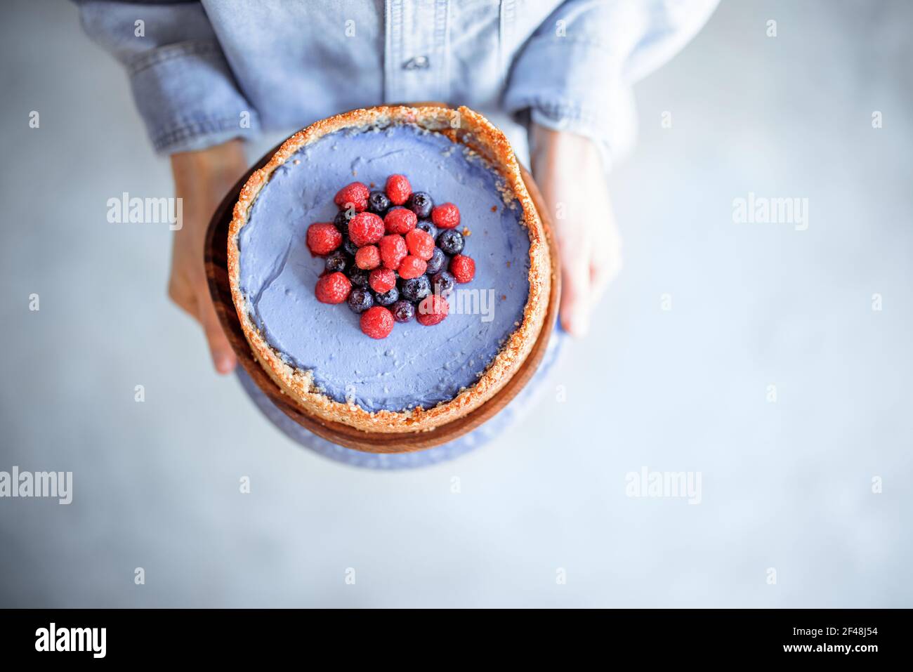 Woman carrying cheesecake decorated with rasberry and blueberry, view ...