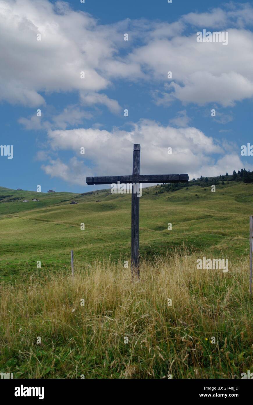 A wooden cross in the mountains next to a hiking path in France region ...