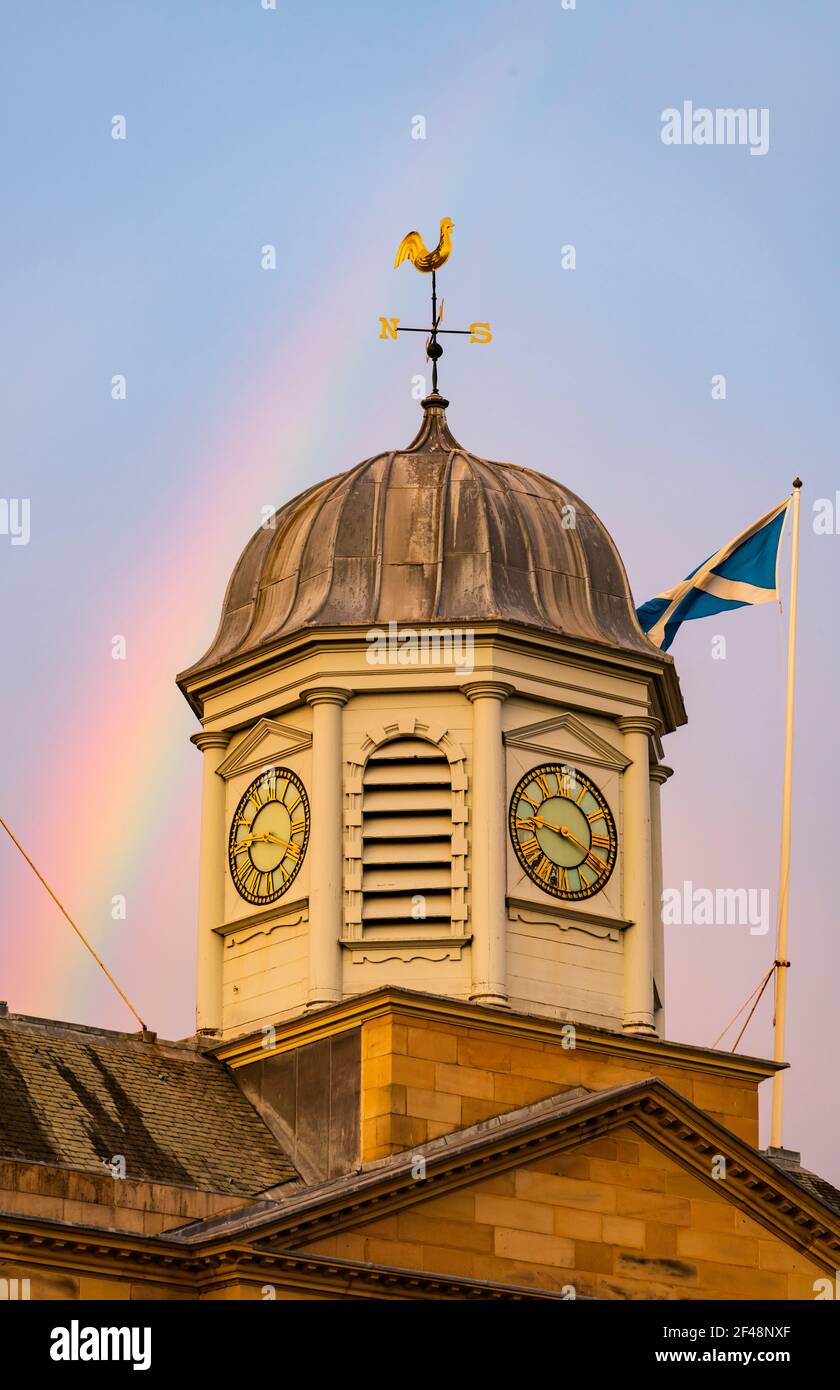 Evening sun rainbow behind the saltire flag, clock and weather vane of ...