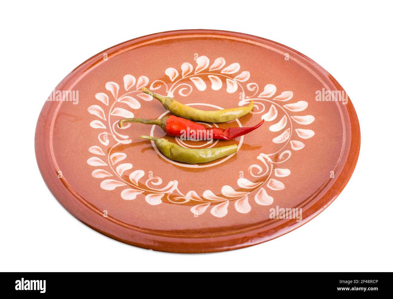 Marinated hot chili peppers on brown clay plate. Isolated on a white ...