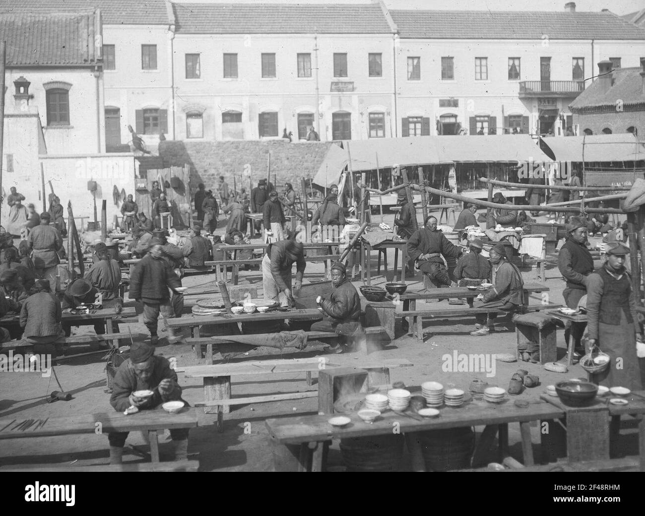 Tsingtau, China. Worker at a meal on wooden tables and wooden benches ...