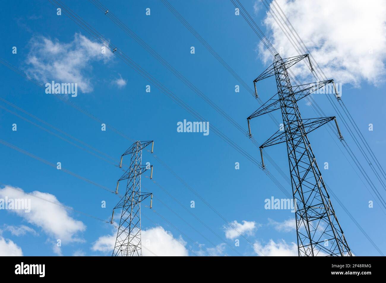 Two giant metal transmission towers reach up high into a blue and ...