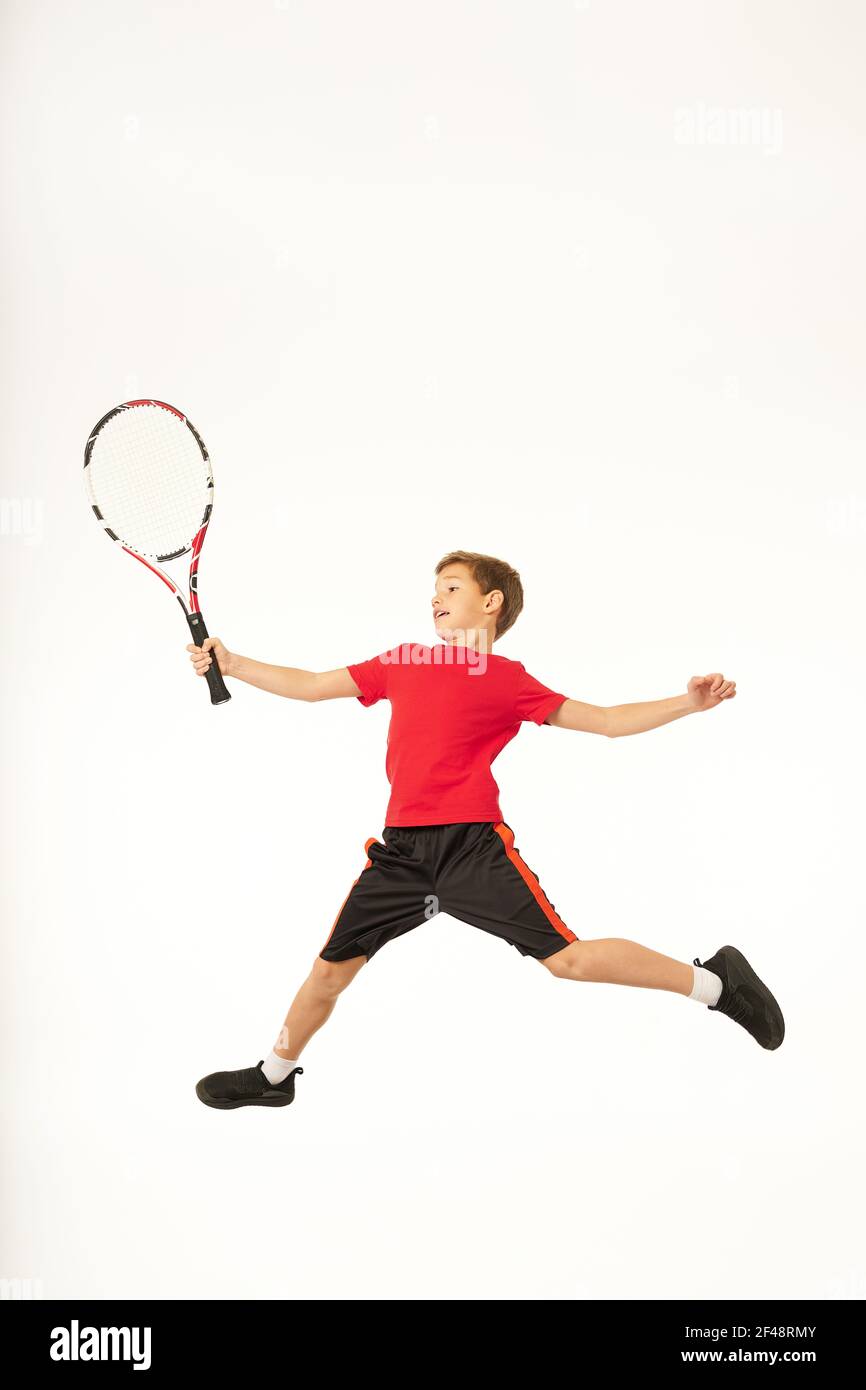 Adorable boy with tennis racket jumping in studio Stock Photo - Alamy