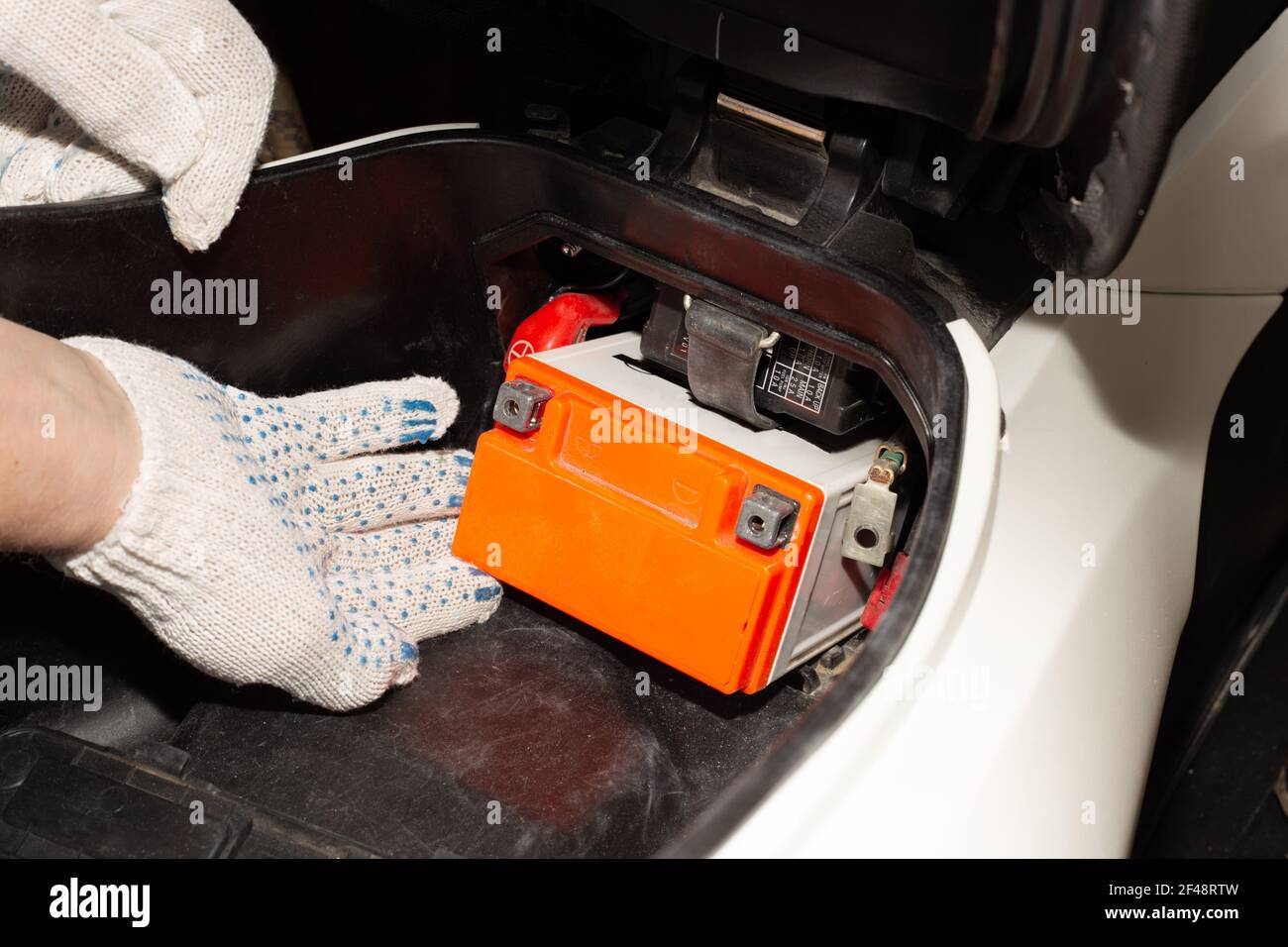 Replacing the motorcycle battery. An auto mechanic in a car service ...