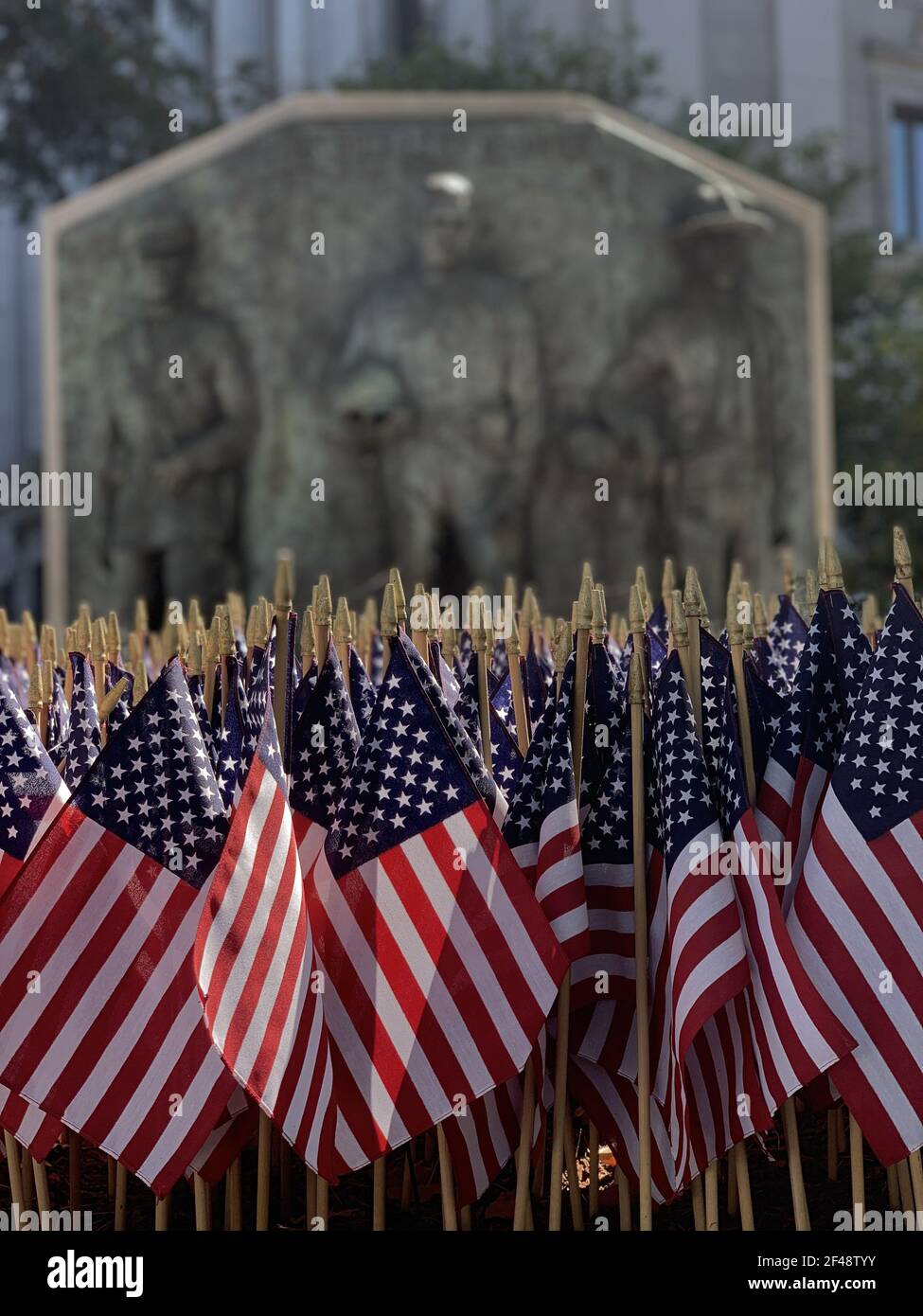 A vertical shot of small US flags with a sculpture in a background ...