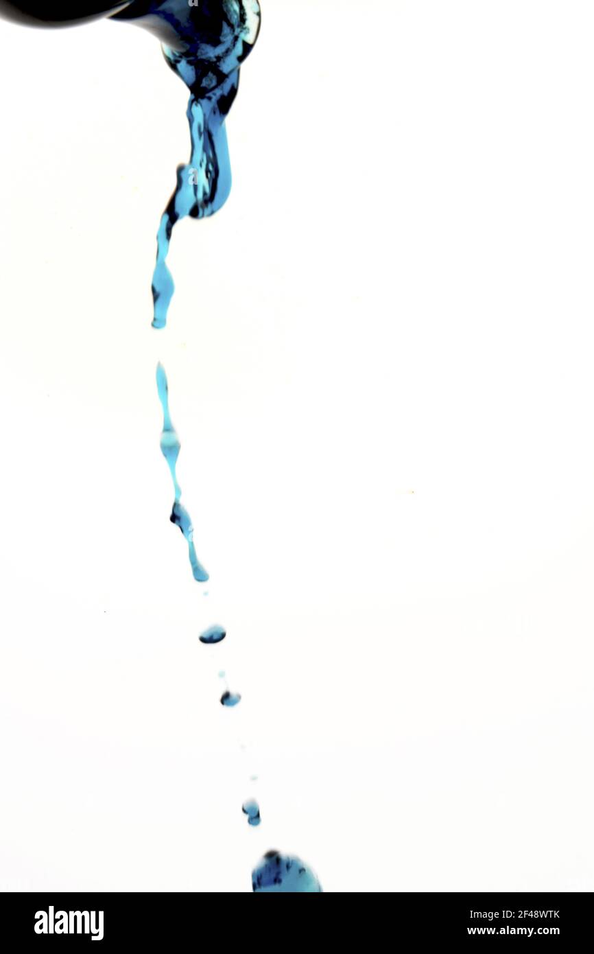 A vertical shot of a blue dripping liquid from a glass bottle isolated ...