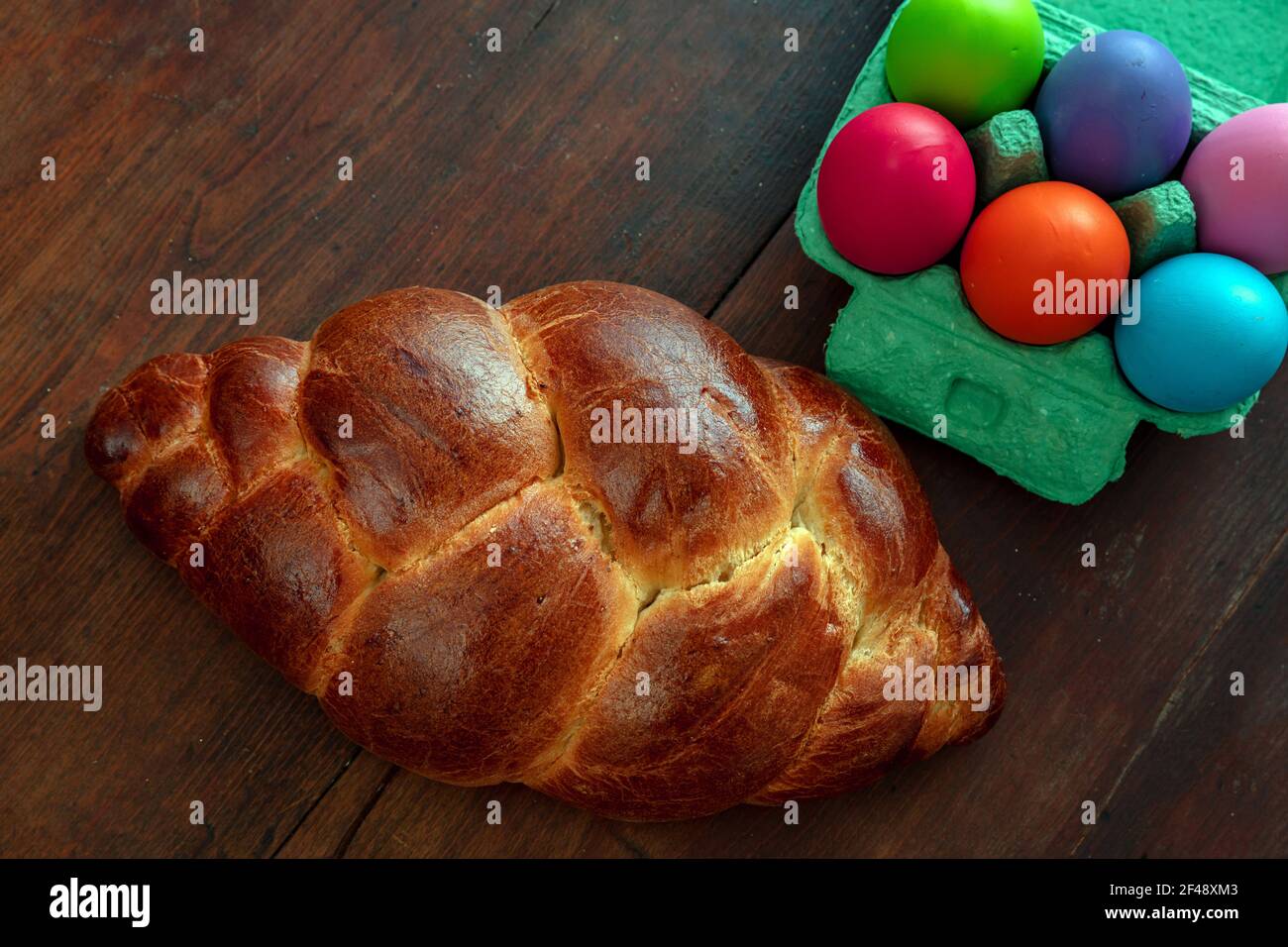 Easter eggs and sweet bread, greek tsoureki cozonac loaf on wood table ...