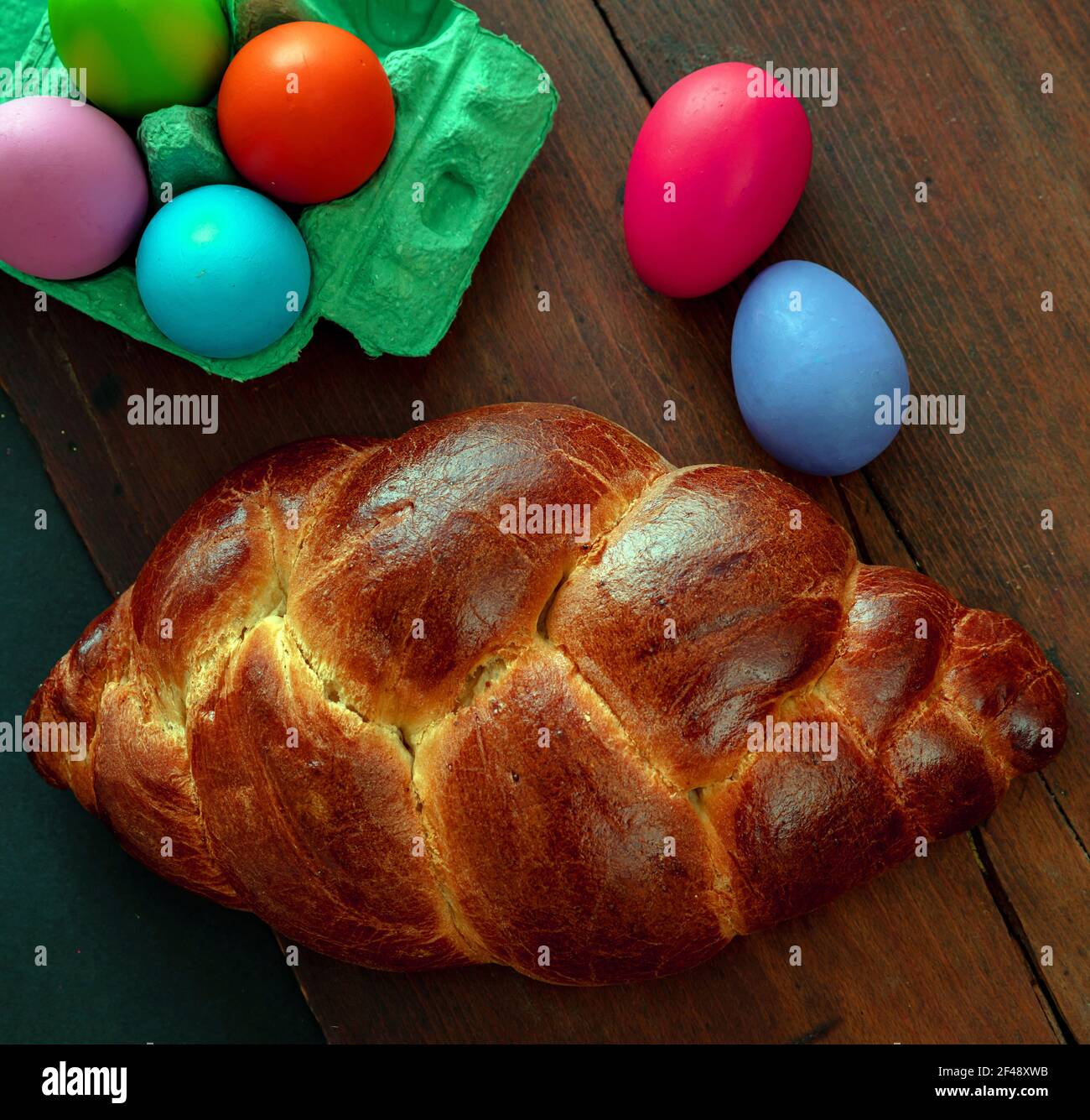 Easter eggs and sweet bread, greek tsoureki cozonac loaf on wood table ...