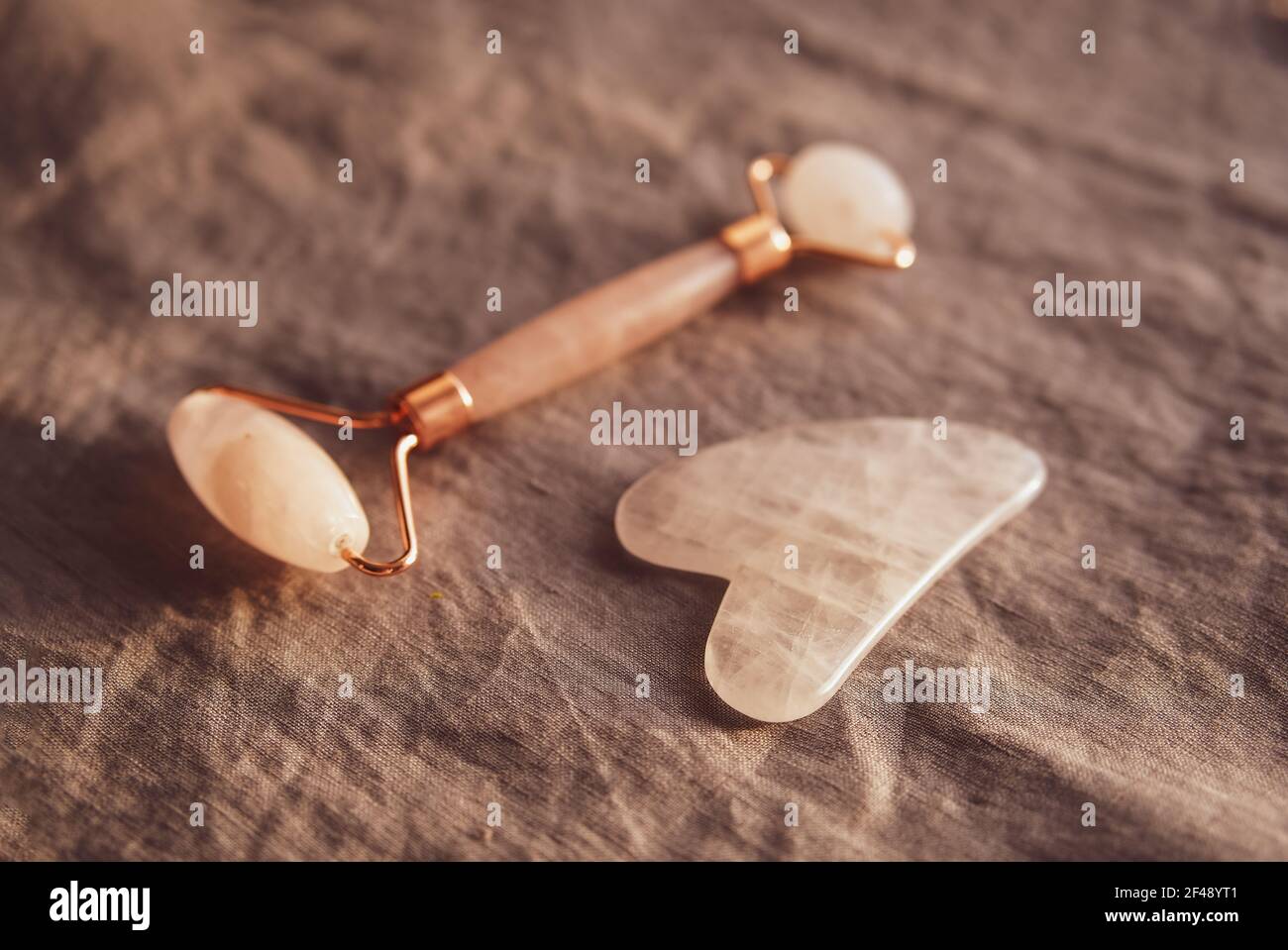 Pink Gua Sha stone and roller for massage and flower Stock Photo - Alamy