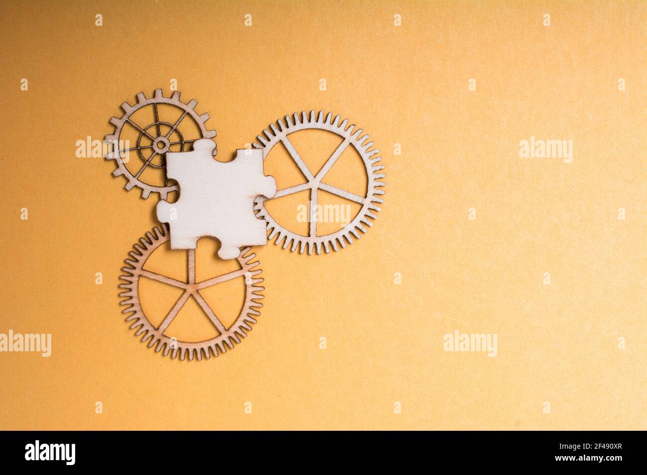 A top view of gear wheels with a piece of a puzzle on an orange ...