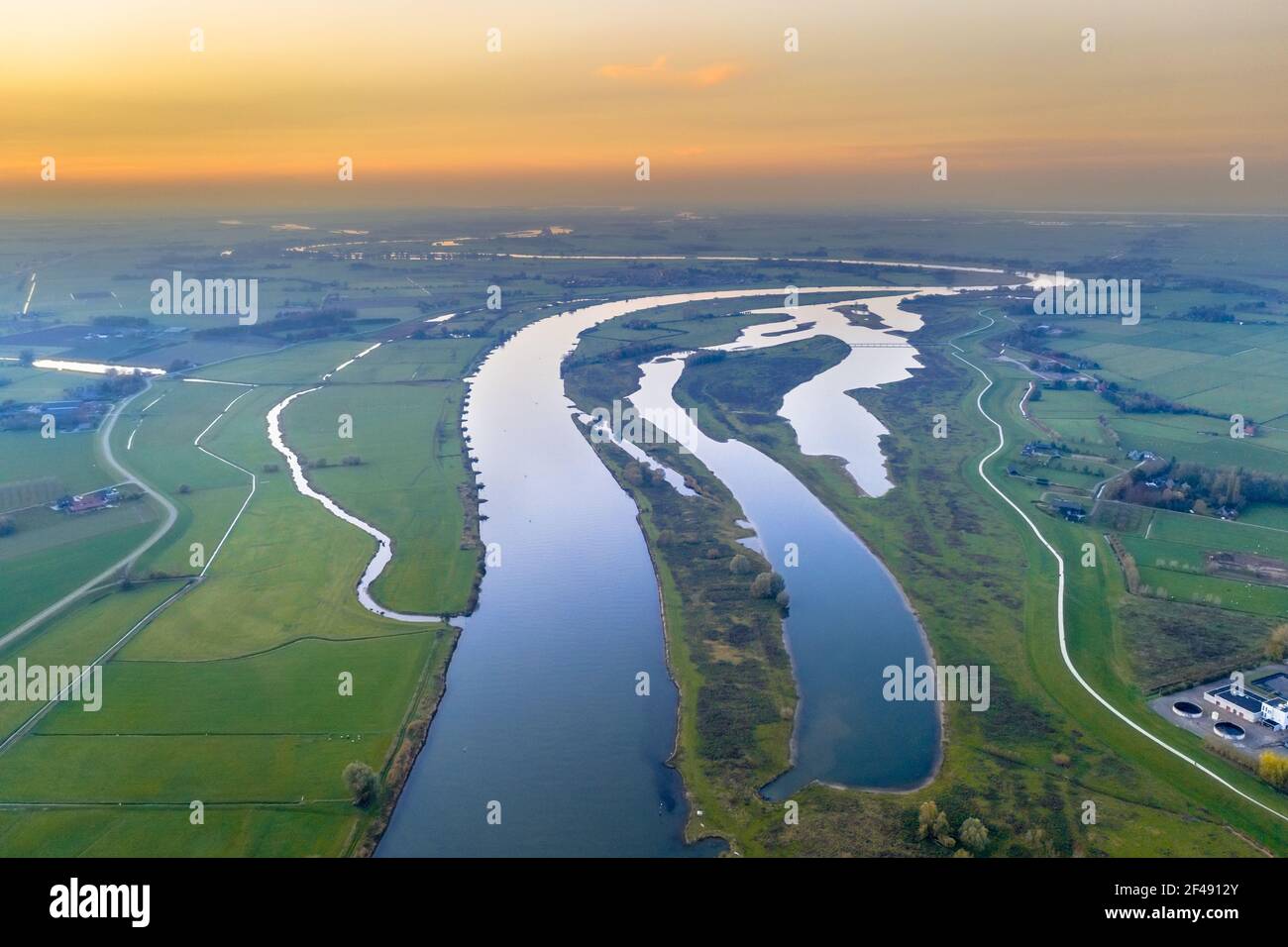 Aerial view of huge lowland river IJssel through sunset landscape ...