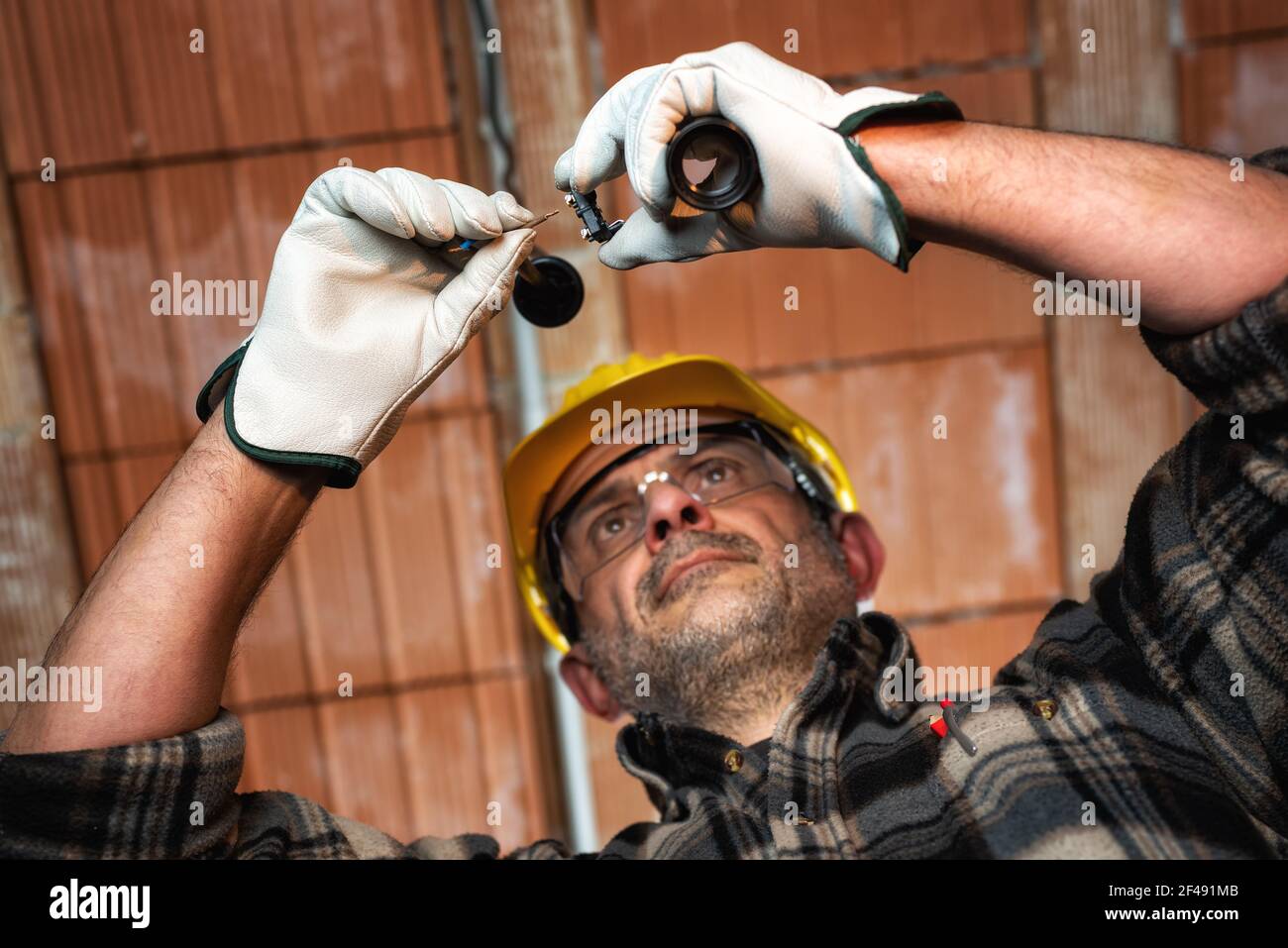 Electrician worker at work replaces the lamp holder in a residential ...