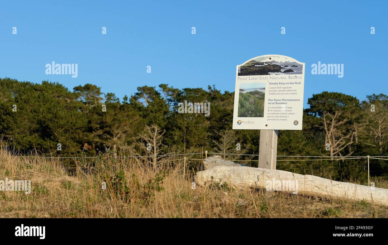Bilingual sign at Point Lobos State Natural Reserve alerting visitors ...