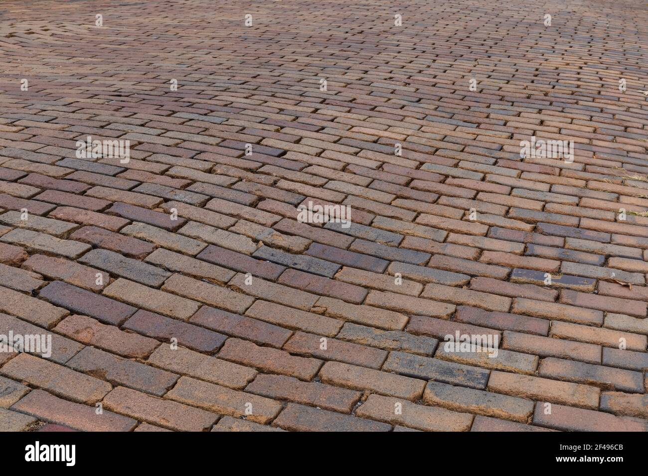 Undulating background of a street paved in red bricks, running bond ...
