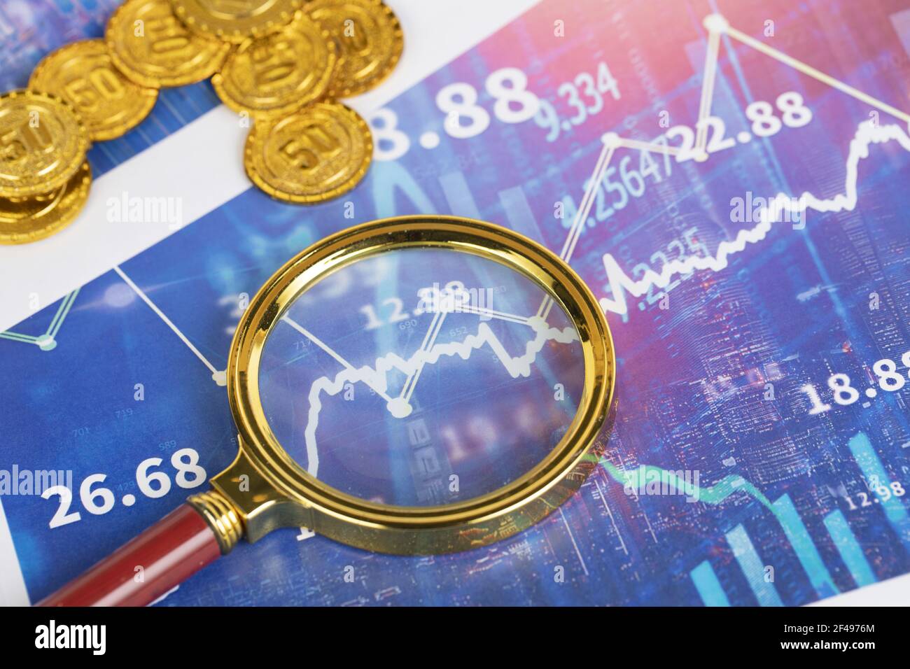 A magnifier and gold coins on stock market chart Stock Photo - Alamy