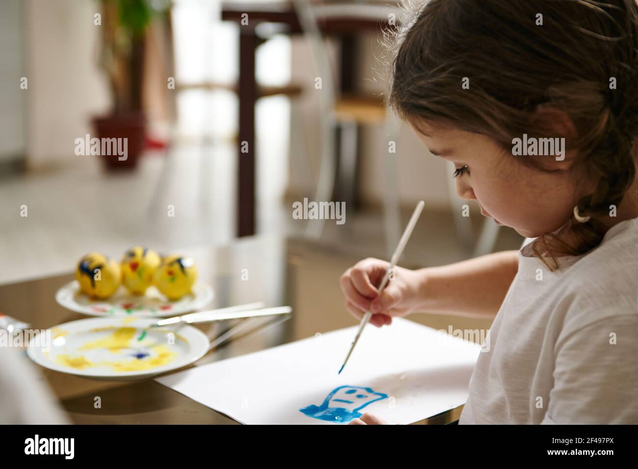 Side view of a cute little girl drawing and coloring with watercolor ...