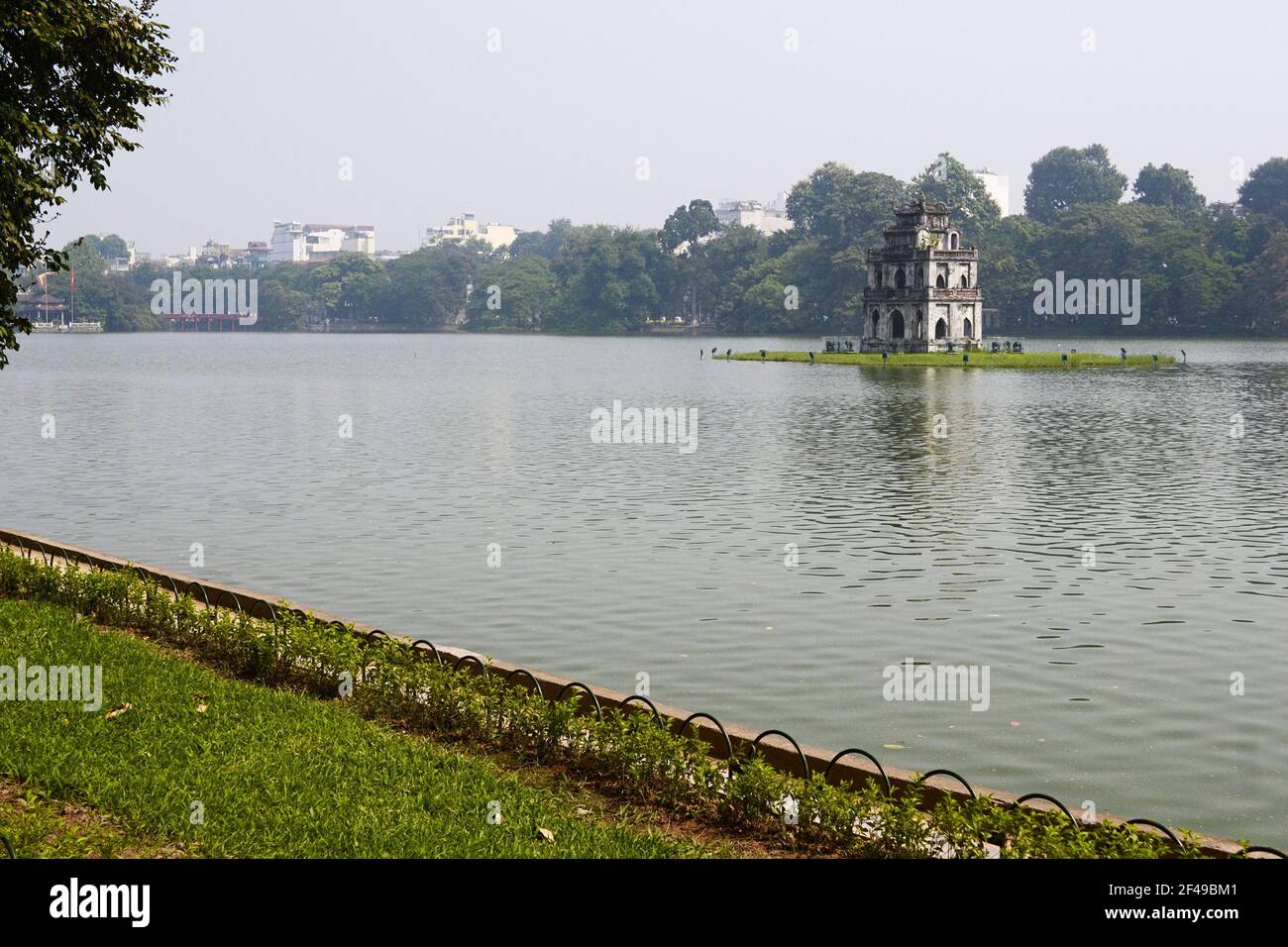 Hoan Kiem Lake also know as Sword Lake with Turtle Tower. Green grass ...