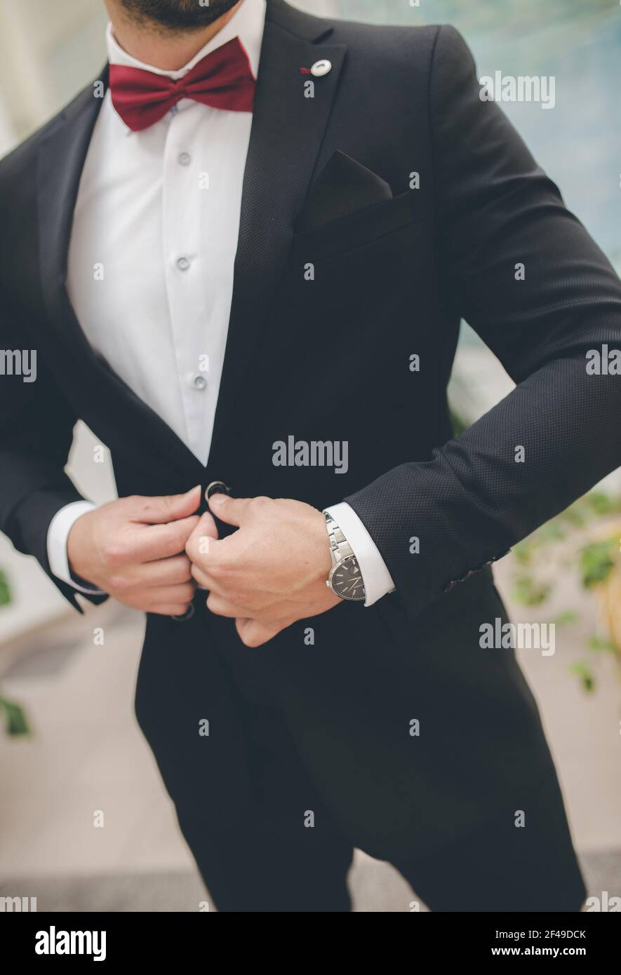 A handsome groom in a stylish suit buttoning up the jacket Stock Photo ...
