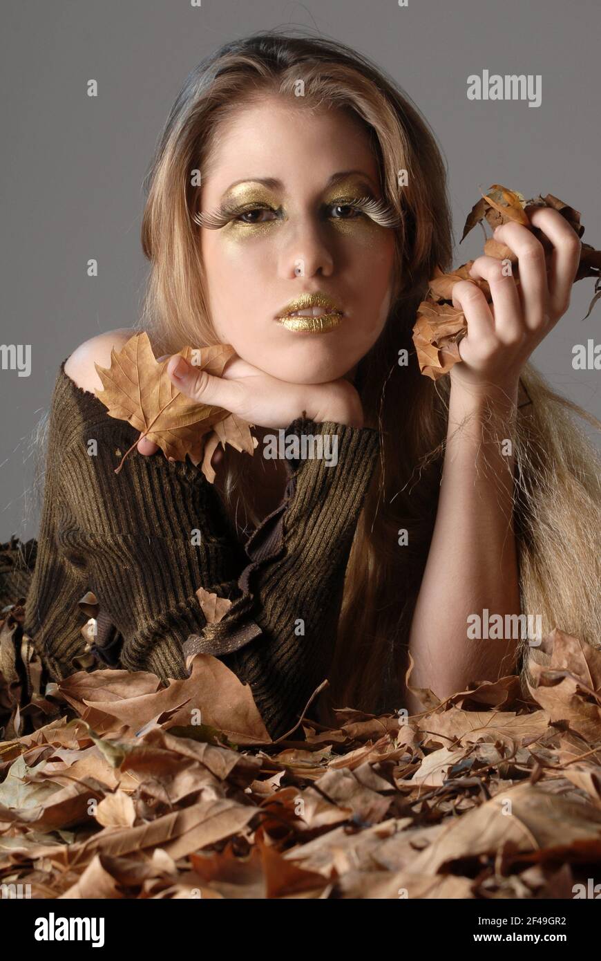 An Argentinian Blonde woman with bright gold makeup and dried leaves in ...