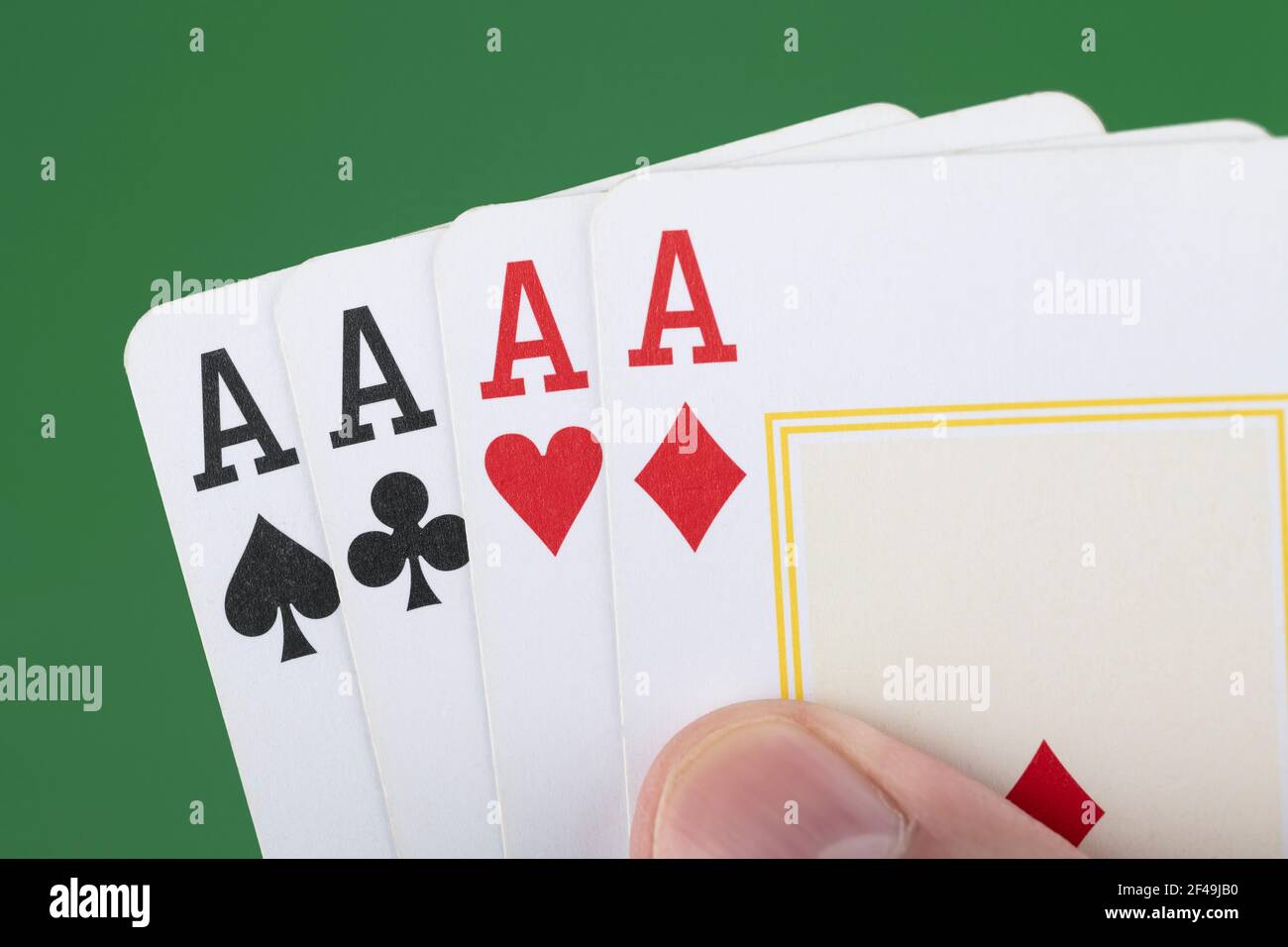 Hand holding 4 aces cards over green background Stock Photo - Alamy