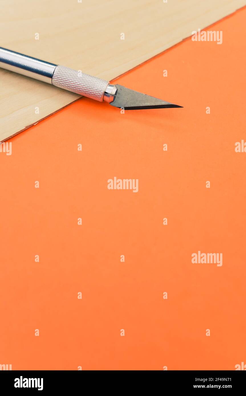 A vertical shot of the metallic scalpel on a plywood surface isolated ...
