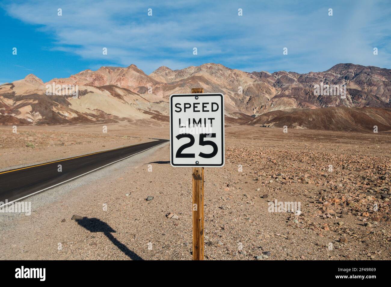 A speed limit sign in front of an empty road leading to colorful ...