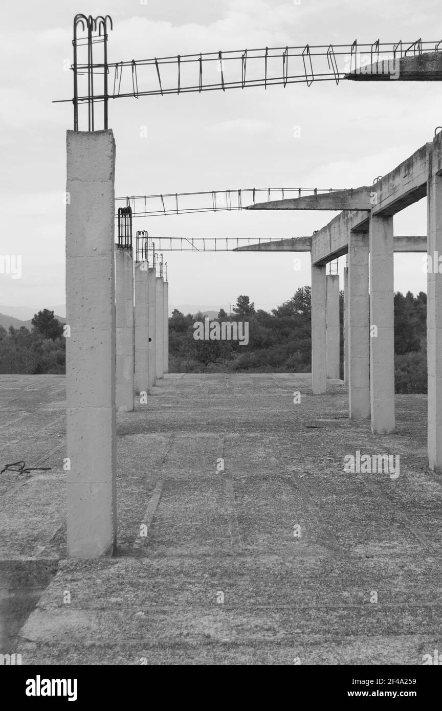 A vertical greyscale shot of concrete columns in a construction site ...