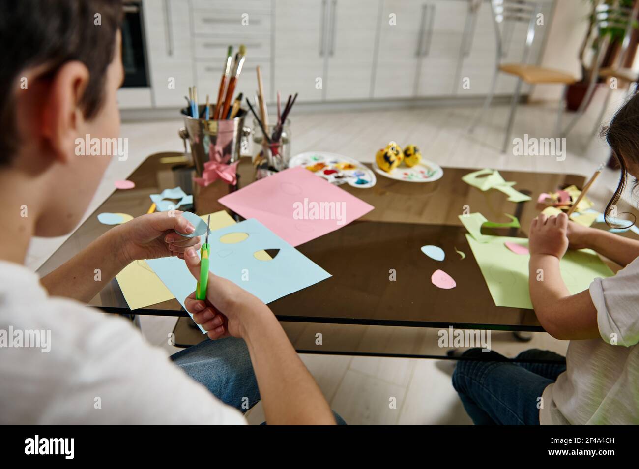 Rear view of school and preschool children drawing and cutting shapes ...
