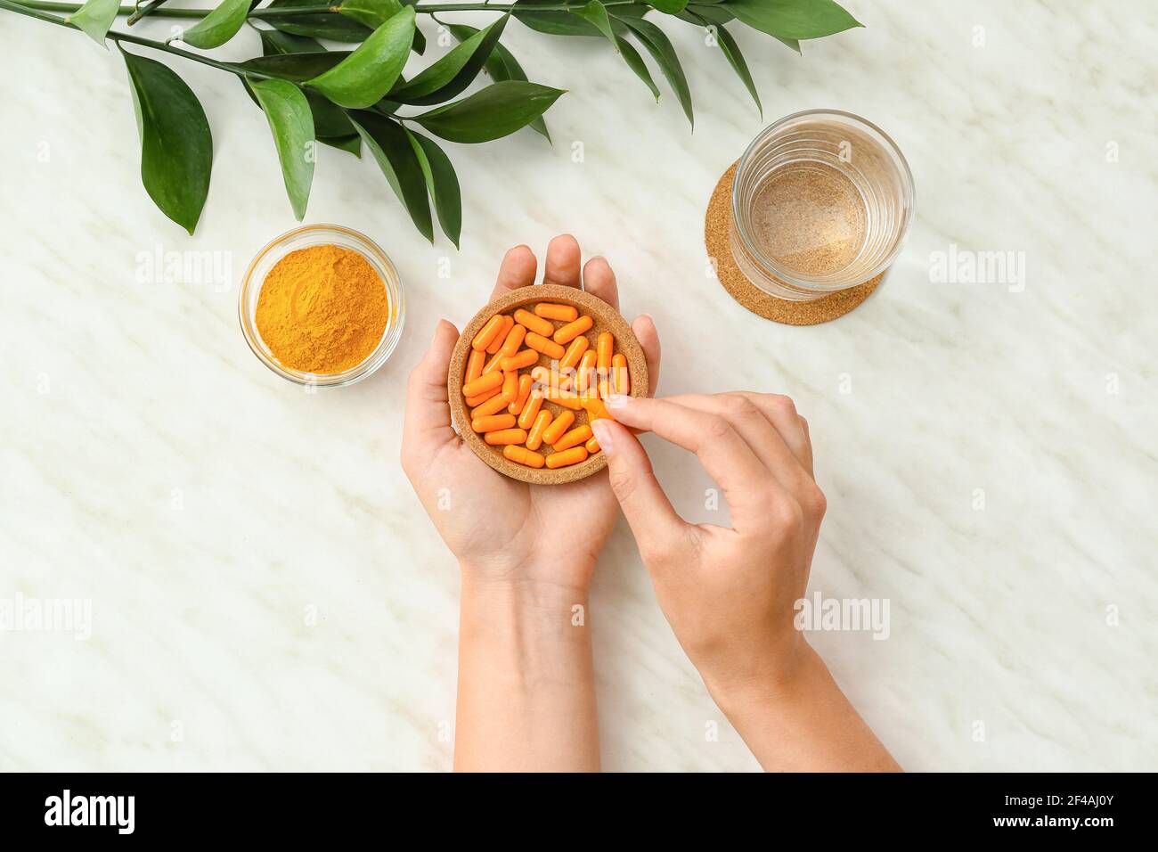 Female hands with turmeric pills on light background Stock Photo - Alamy