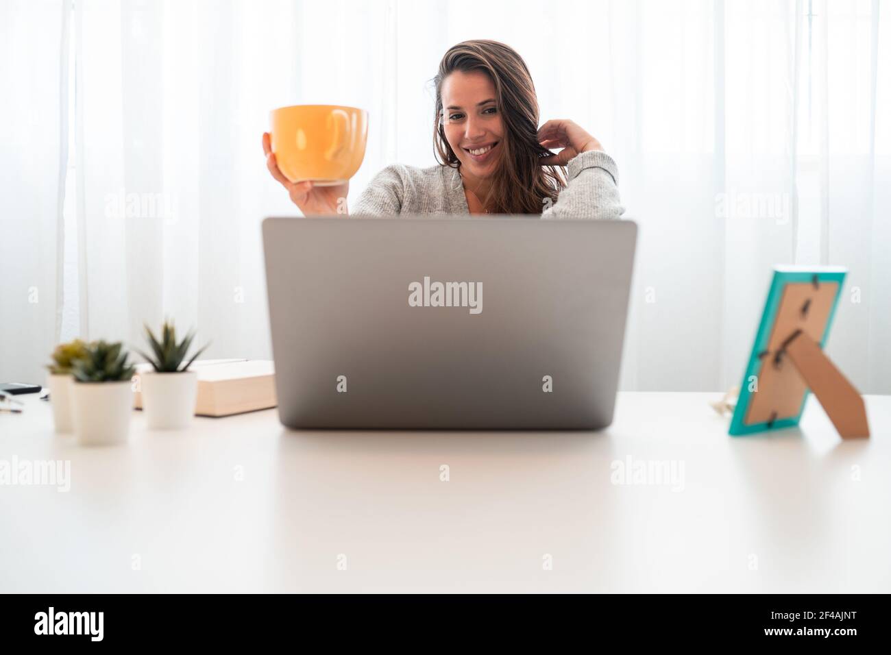 young woman teleworking at home with computer drinking coffee Stock ...