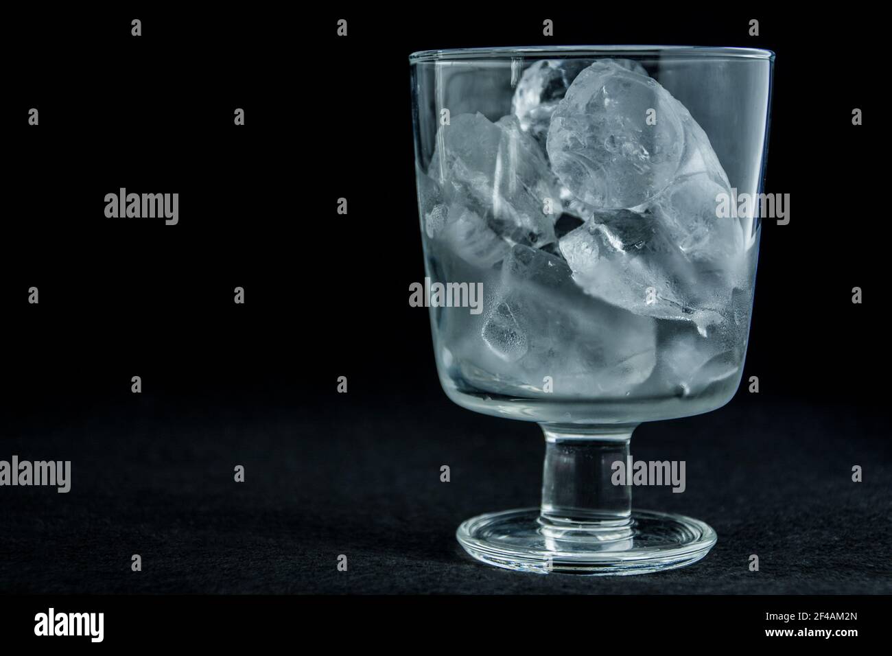Glass full of ice on a black background Stock Photo - Alamy