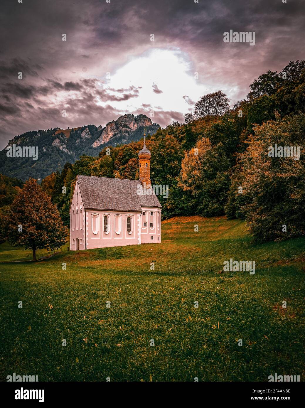 A vertical shot of a lonely church on a mountainside with a bright sky ...