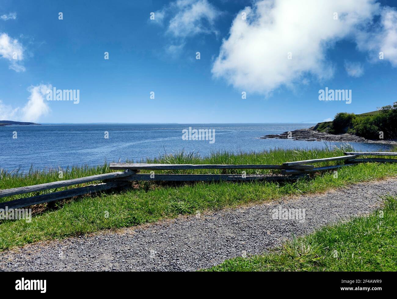 Walkway trail with wooden fence and grass field next to ocean Stock ...