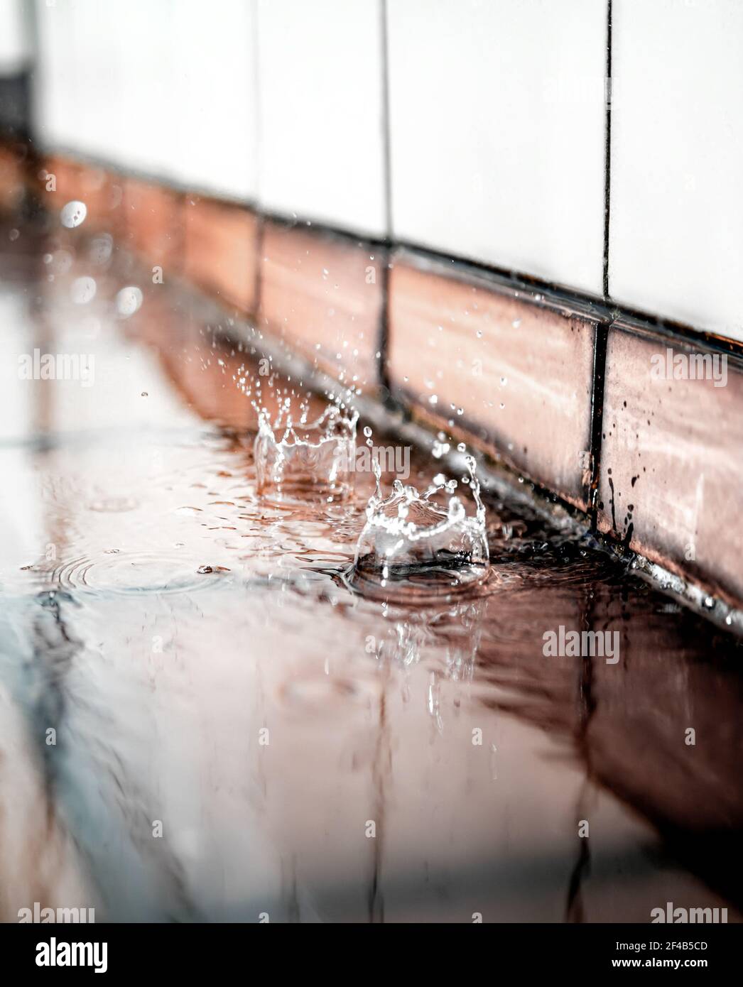 Waterdrop splashes in motion. Rain drops falling on brick tiles in ...
