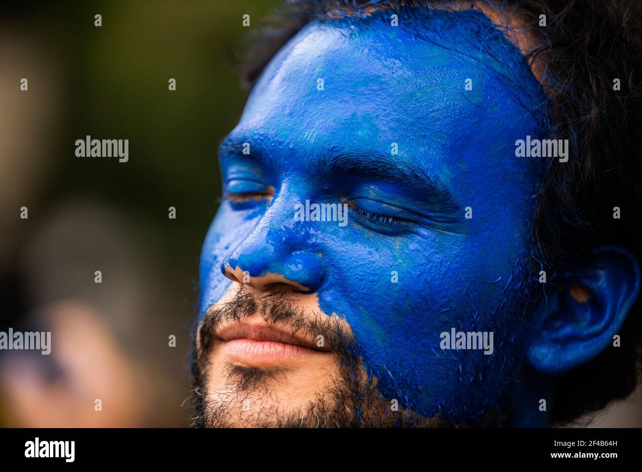 An environmental activist is seen with blue paint on his face during ...