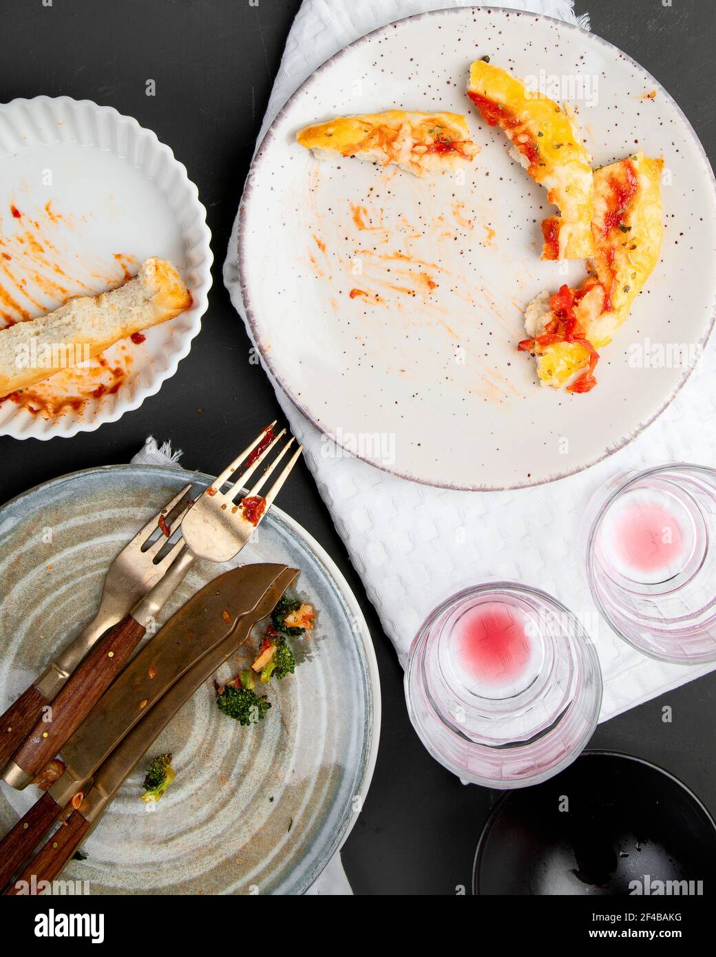 Pile of empty and dirty plates with food leftovers on dark background ...