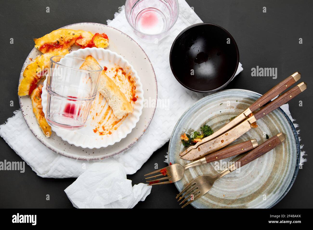 Pile of empty and dirty plates with food leftovers on dark background ...