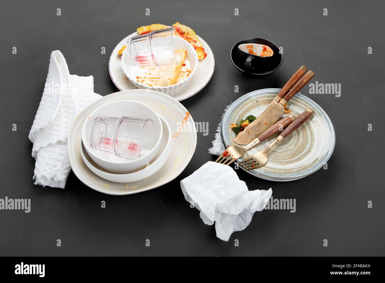 Pile of empty and dirty plates with food leftovers on dark background ...