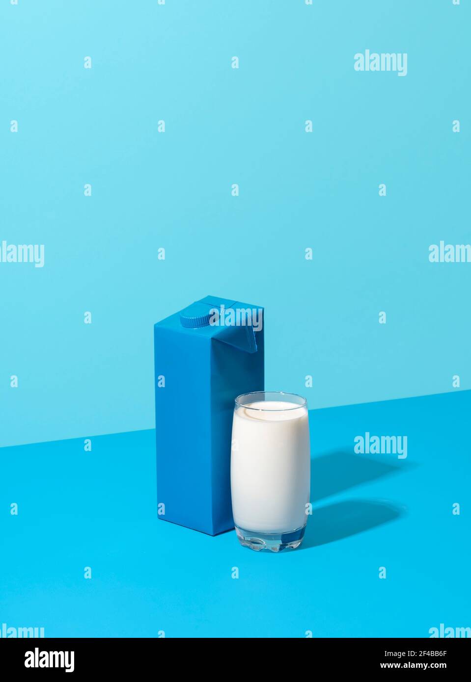 Milk box and a glass of milk on a blue-colored table. Blank carton box ...