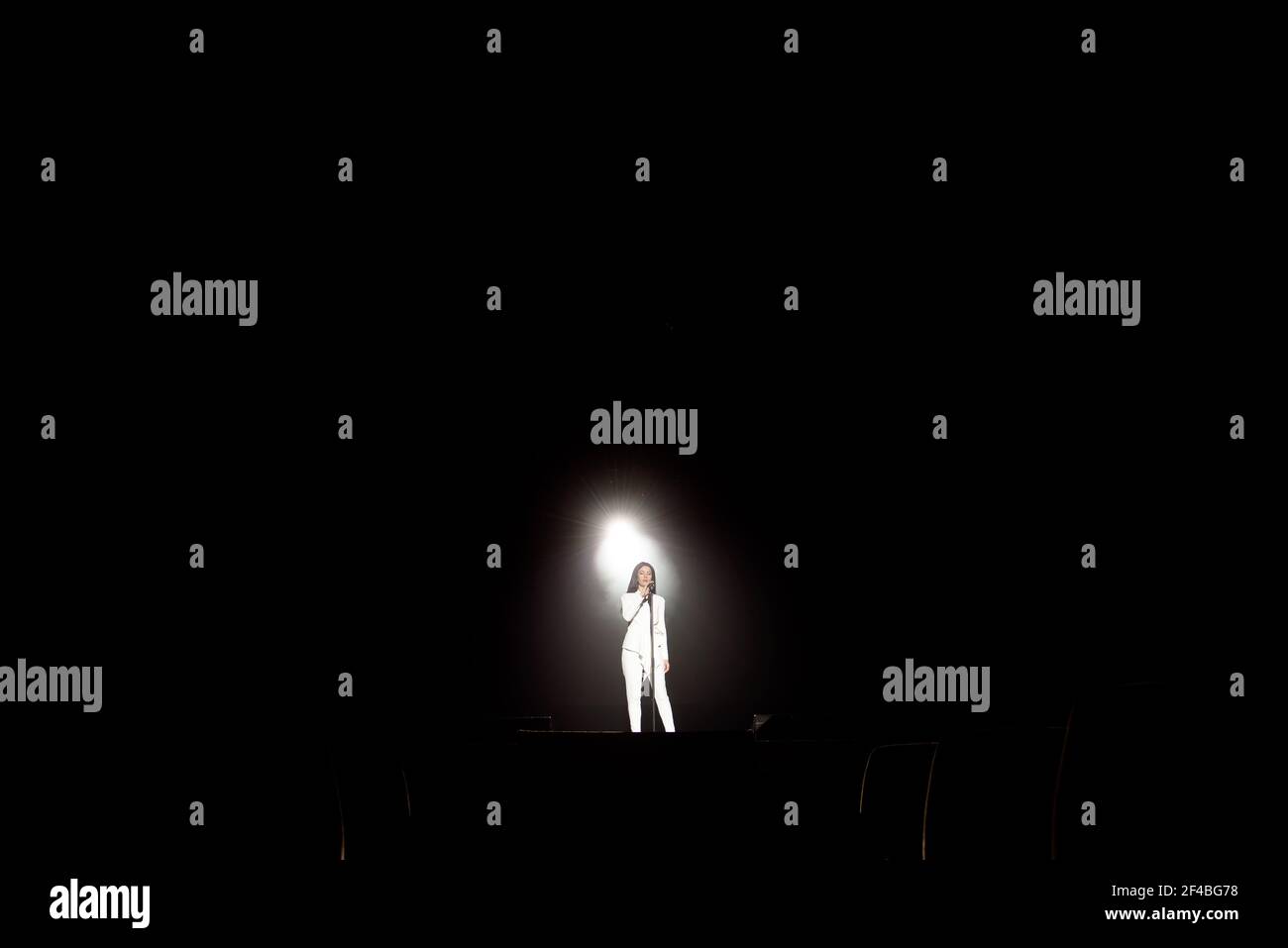 Singer on stage in a beam of white light Stock Photo - Alamy