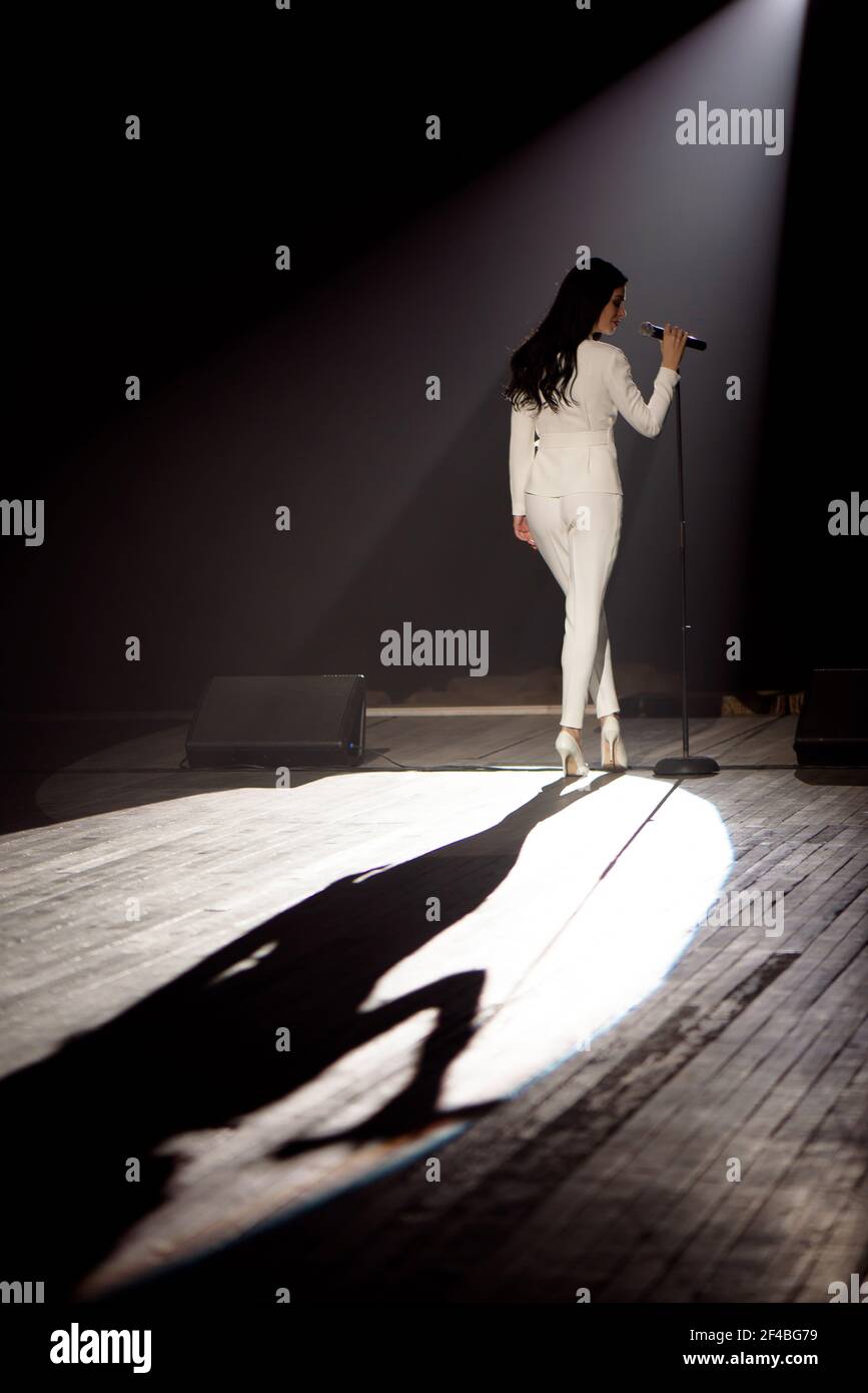 Singer on stage in a beam of white light Stock Photo - Alamy