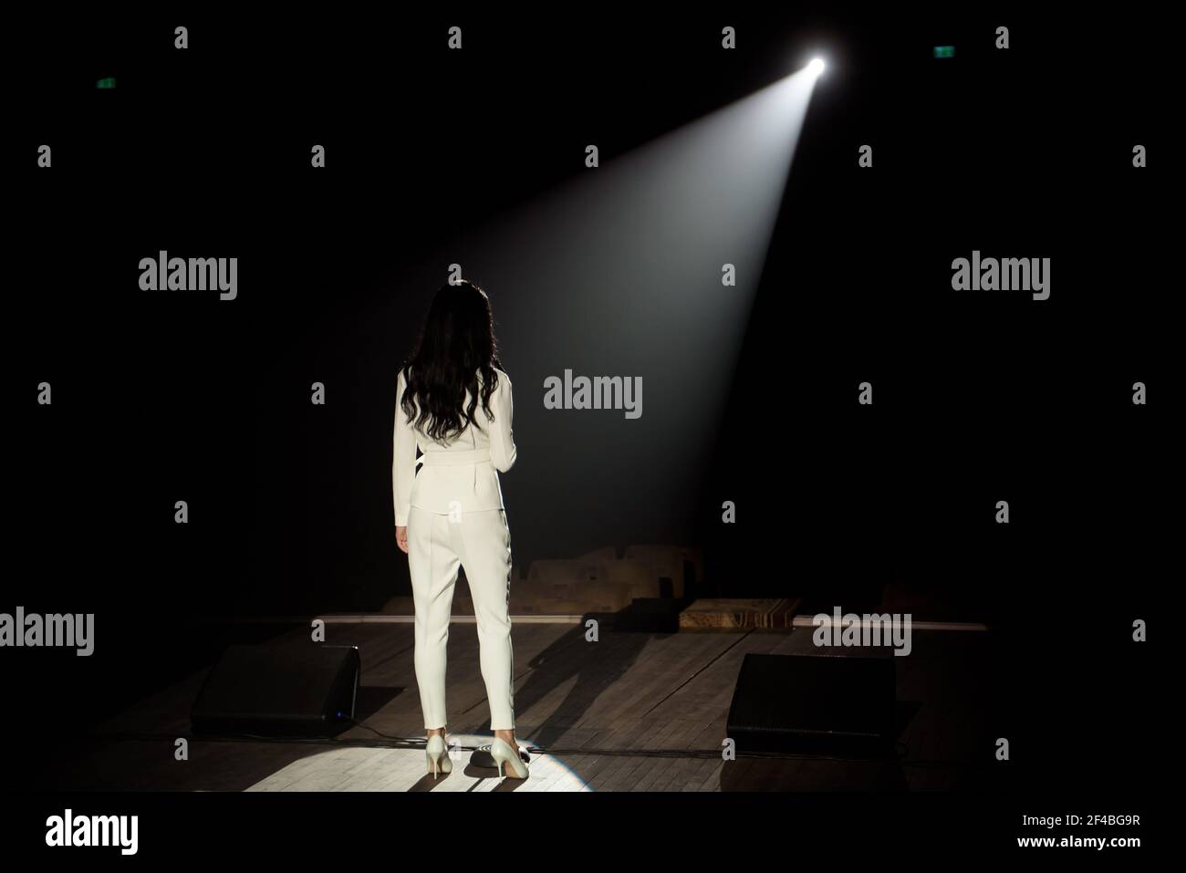 Back view of a singer with microphone singing a song on stage in white ...