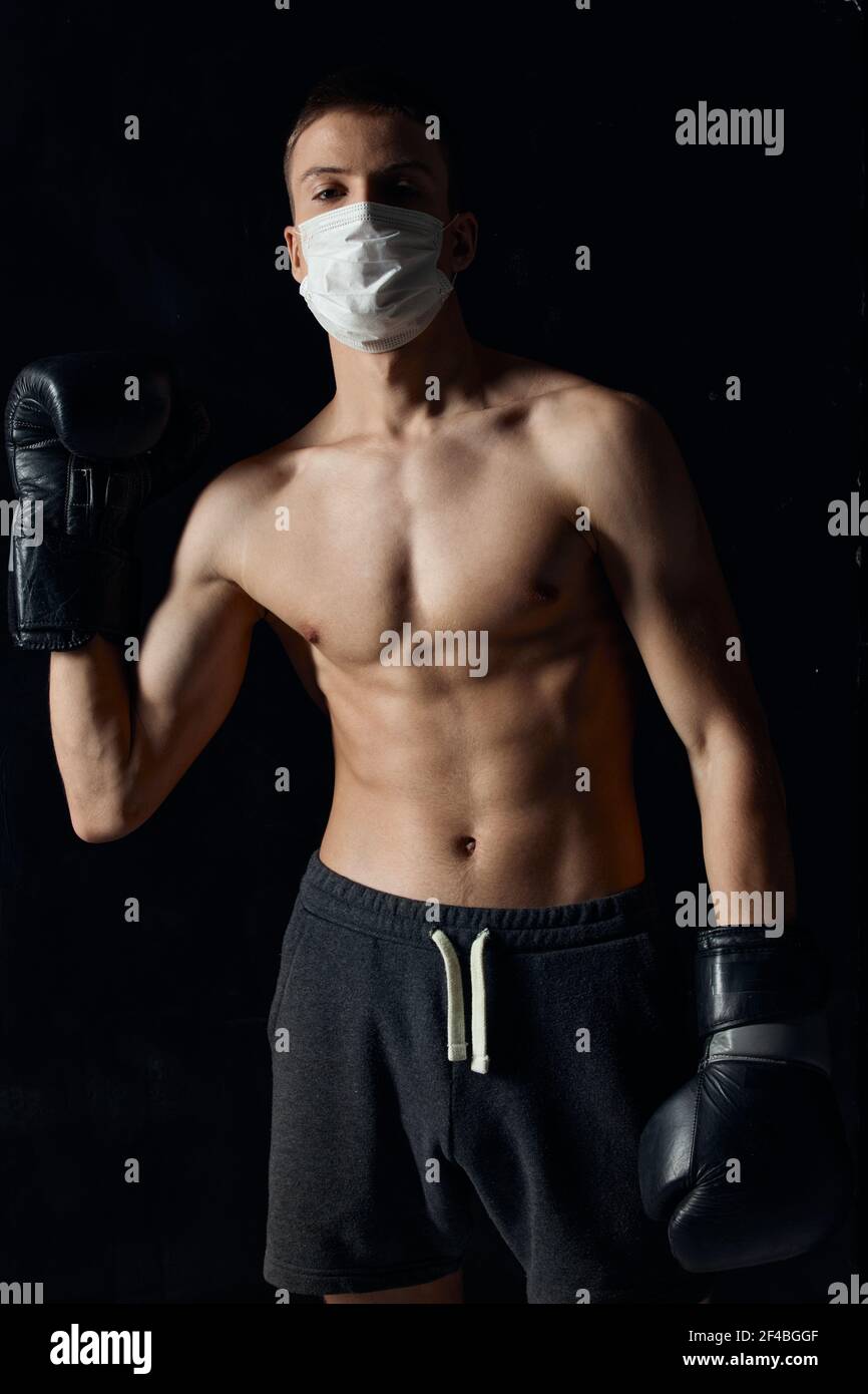 athlete in medical mask and in boxing gloves on isolated background ...