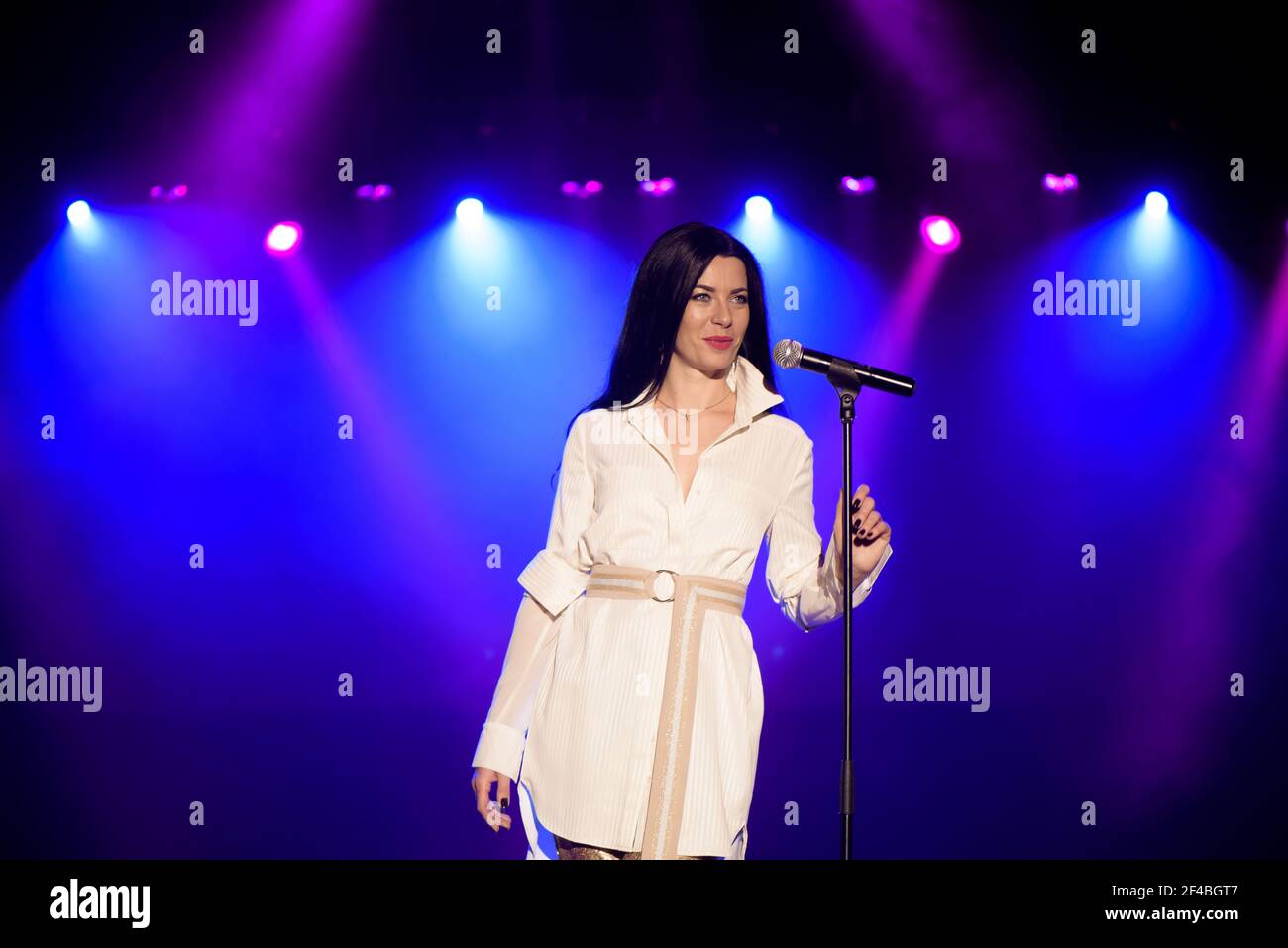 Cool singer with microphone on bright backlit stage in bright blue ...