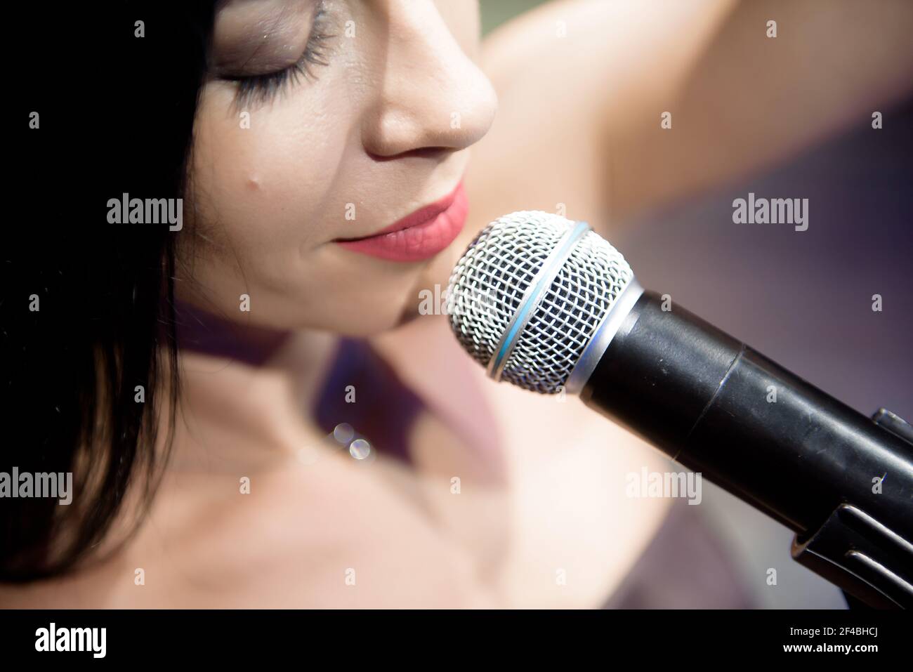 Female singer, performing her vocal sound on the scene with spotlight ...