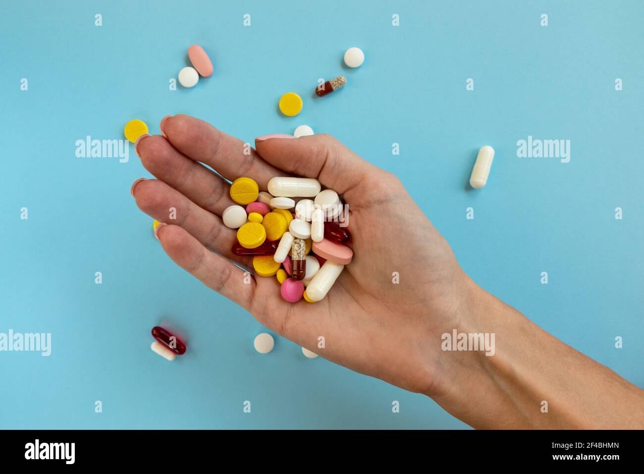 Woman holding in hand different medical pill on light blue background ...