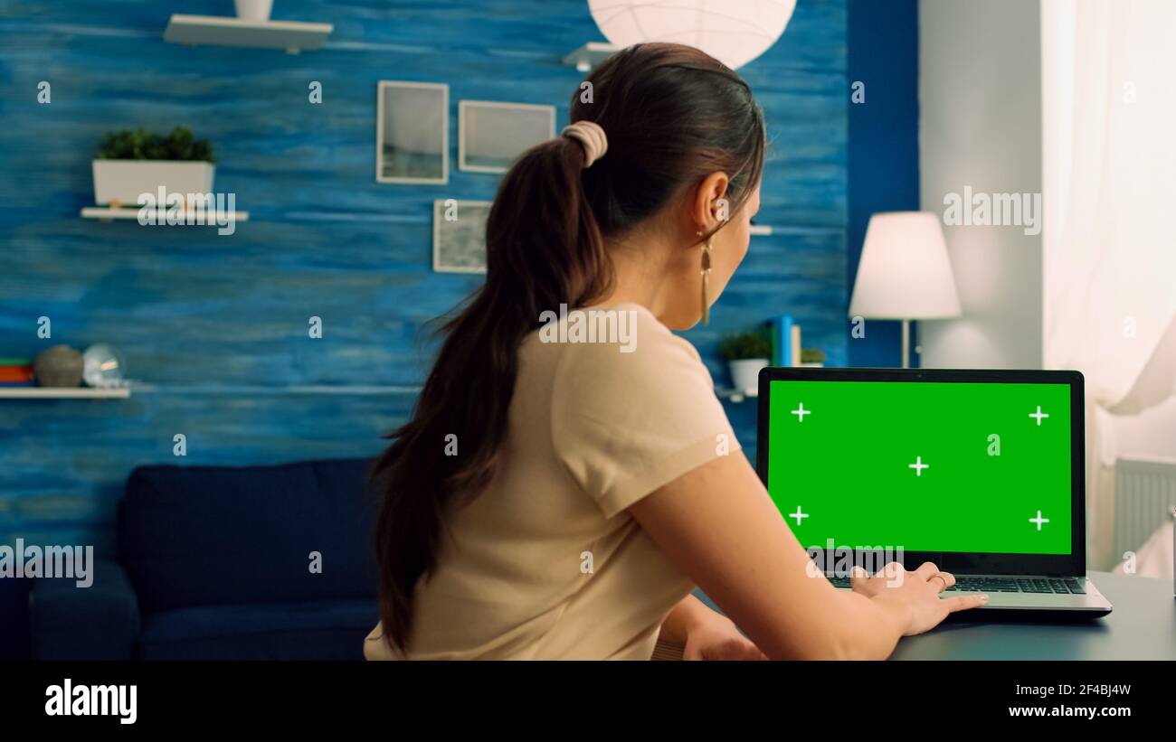 Caucasian female working on laptop computer with mock up green screen chroma key display for ...