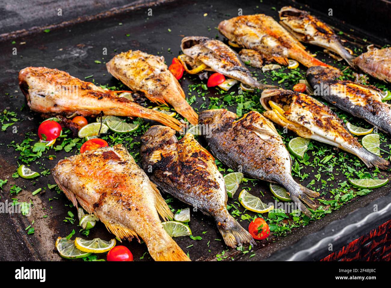 fried fish seasoned with lemon and tomatoes Stock Photo - Alamy