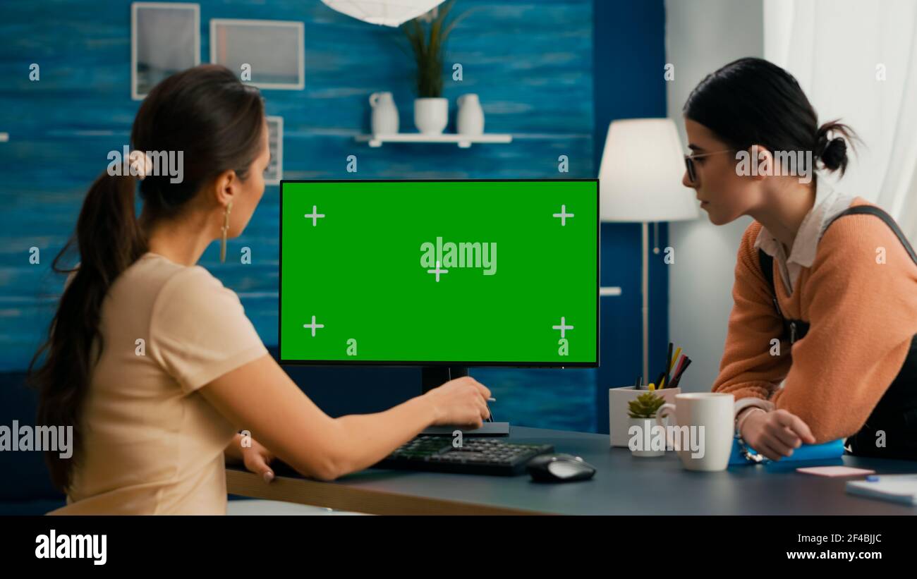 Two friends sitting in front of mock up computer green screen chroma ...