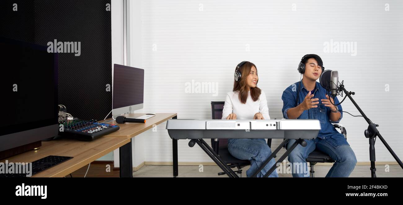 Young asian man with headphones singing with microphone in front of ...